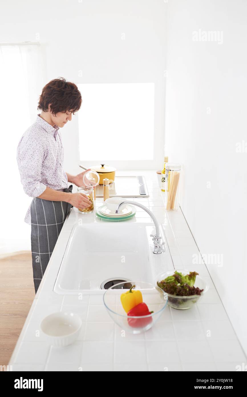 Man in an apron holding a glass container in the kitchen Stock Photo ...