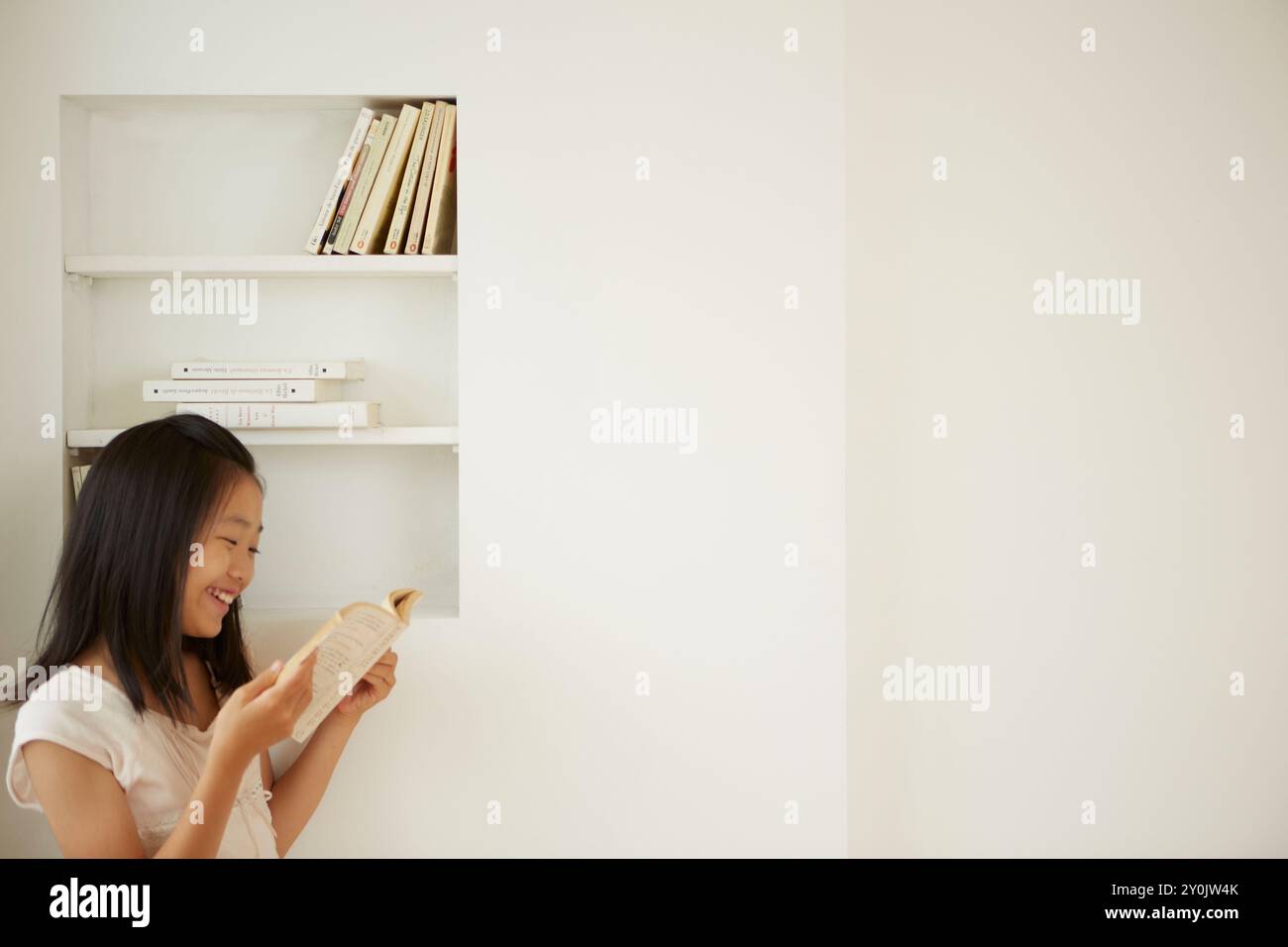 Woman reading in front of a bookcase Stock Photo - Alamy