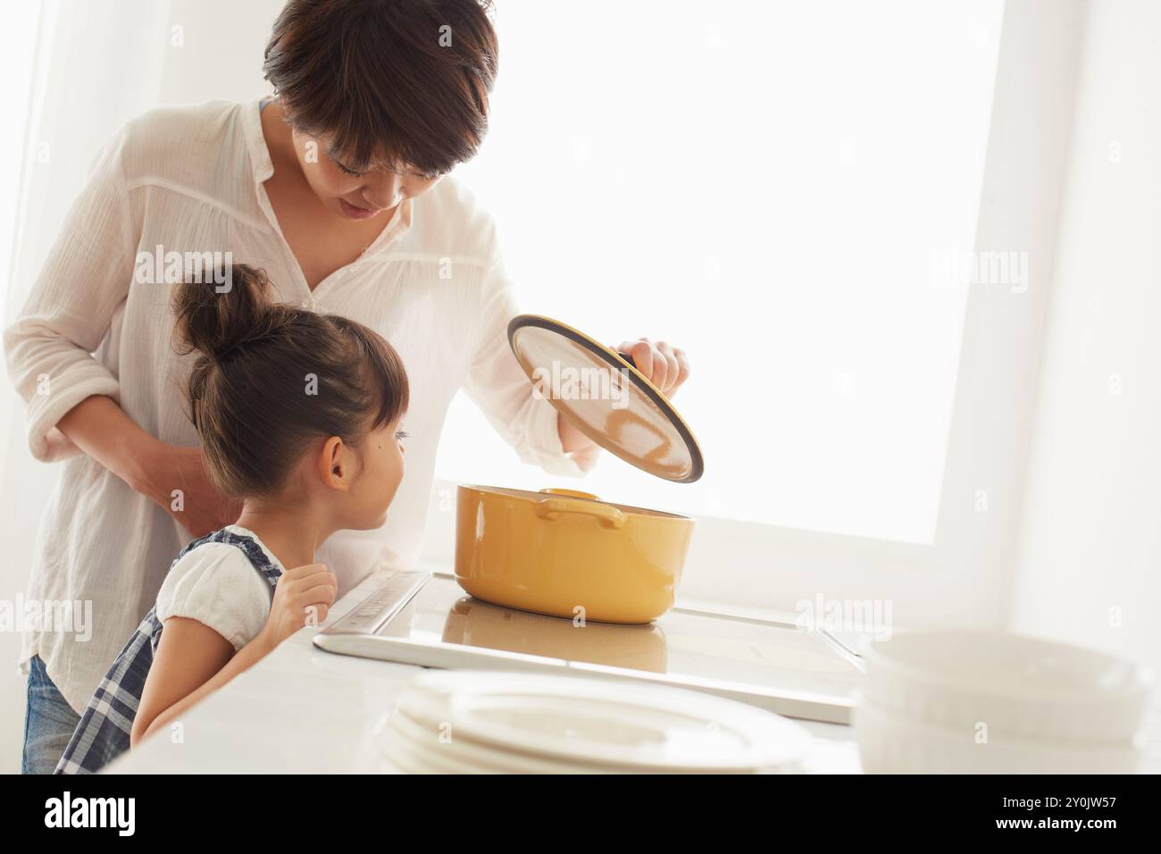 Girl helping her mother while cooking in the kitchen Stock Photo - Alamy