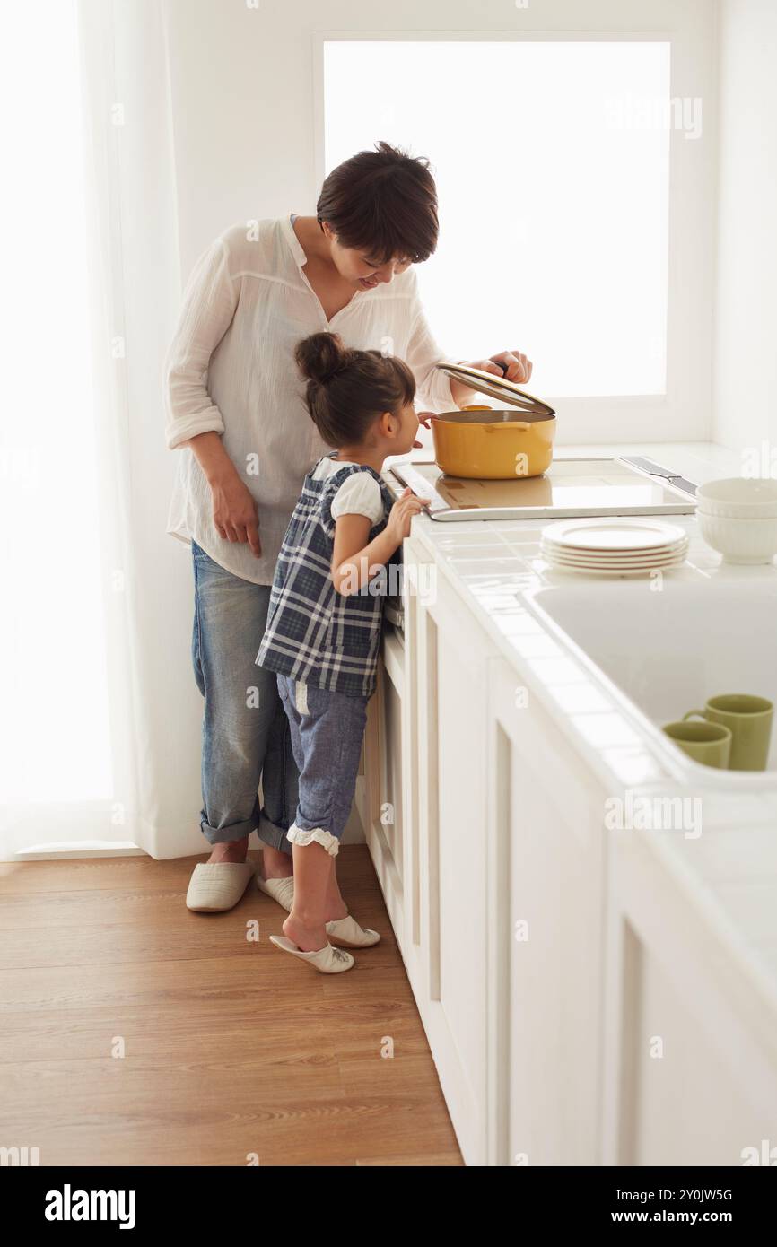 Girl helping her mother while cooking in the kitchen Stock Photo - Alamy