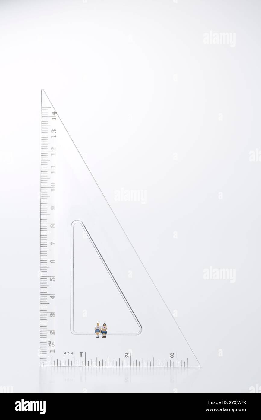 Two student figures sitting on triangle ruler Stock Photo - Alamy