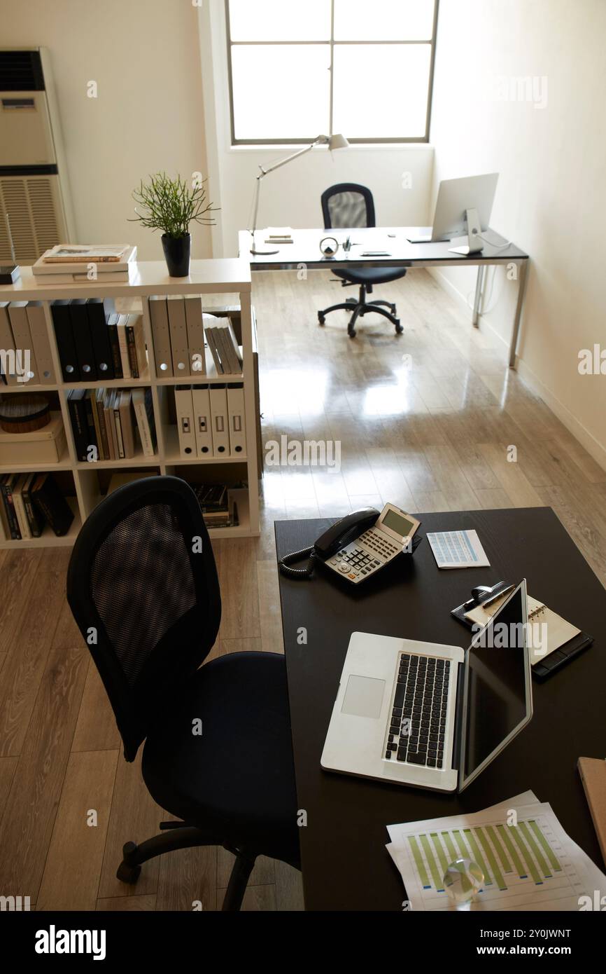 Two desks placed by the window and documents and a personal computer on ...