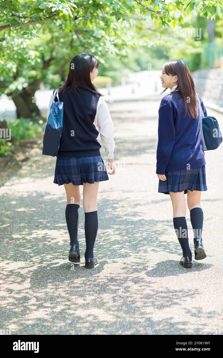 Two Japanese high school girls walking down a tree lined road Stock ...