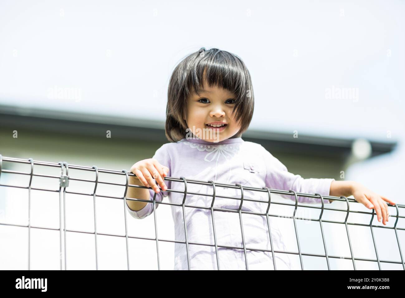 Girl leaning forward from the fence Stock Photo - Alamy