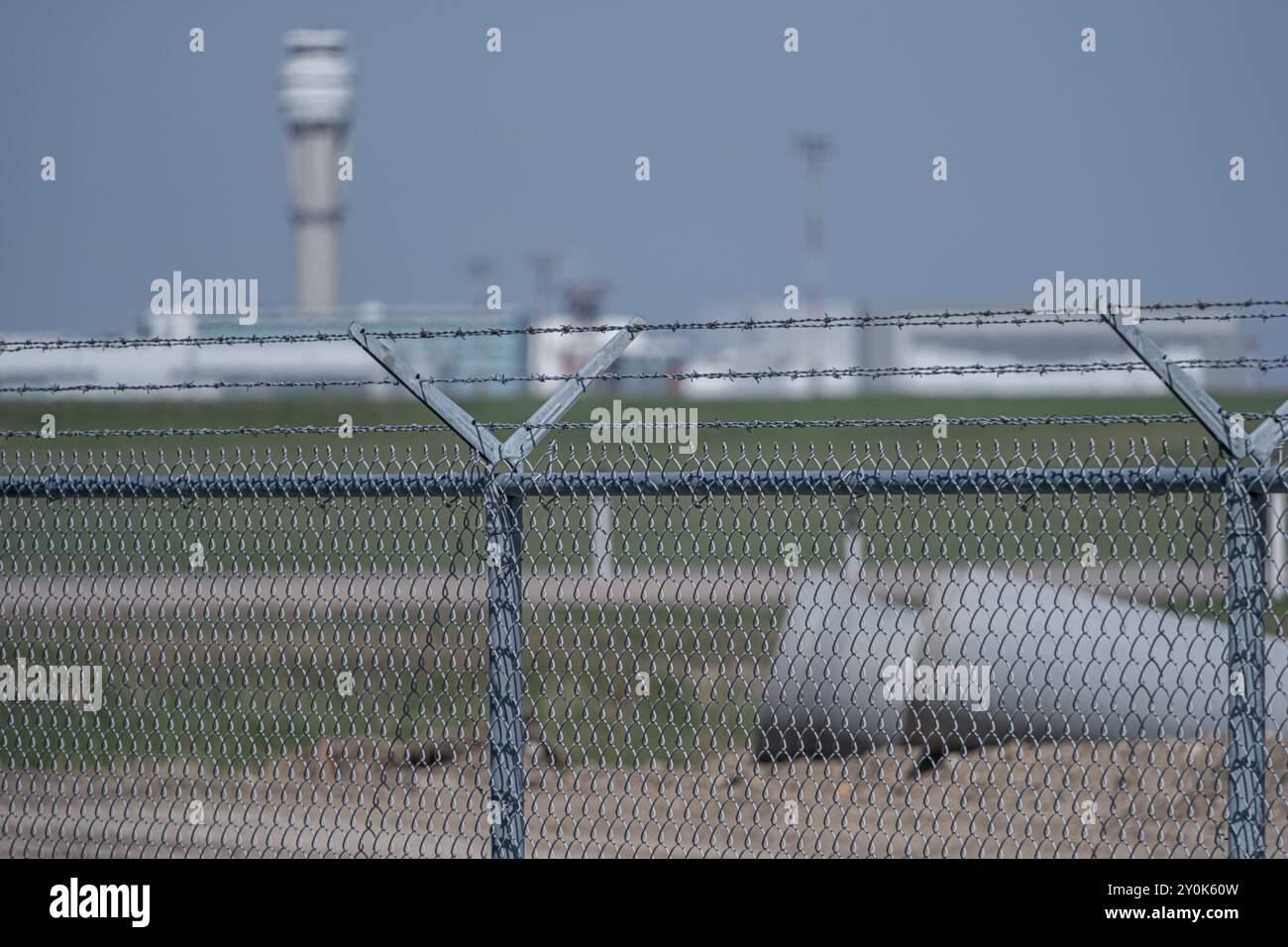 Airport security fence with control tower in background Stock Photo - Alamy