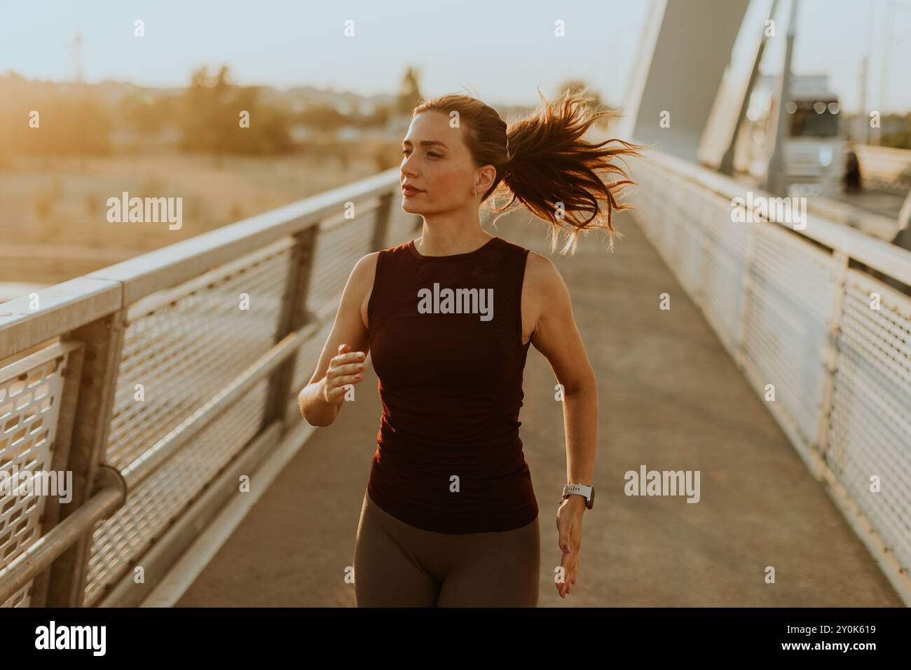 Focused female runner moves gracefully across a bright bridge, enjoying ...