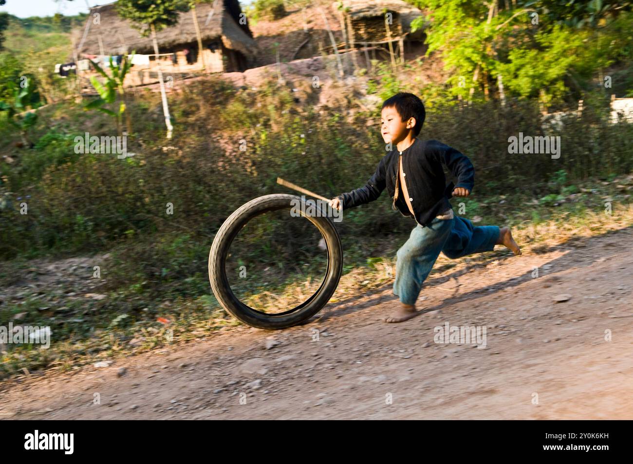 A boy plays with a wheel. this is a common game in rural villages in ...