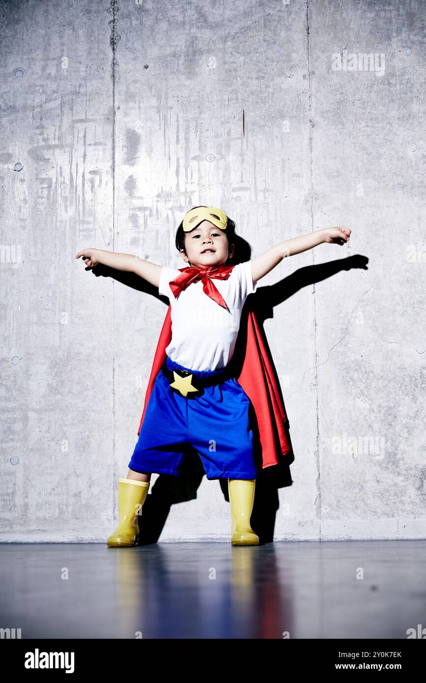 Hero boy striking a pose in front of a concrete wall Stock Photo - Alamy