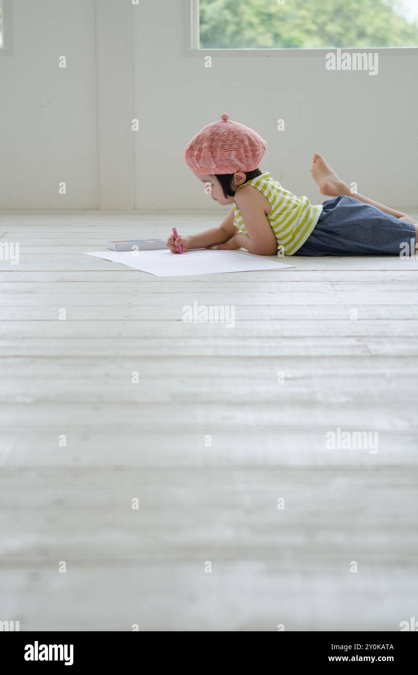 Girl lying on the floor while drawing pictures Stock Photo - Alamy