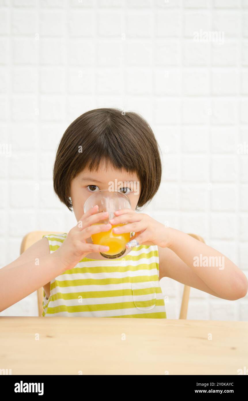 Girl drinking juice sitting on a chair Stock Photo - Alamy