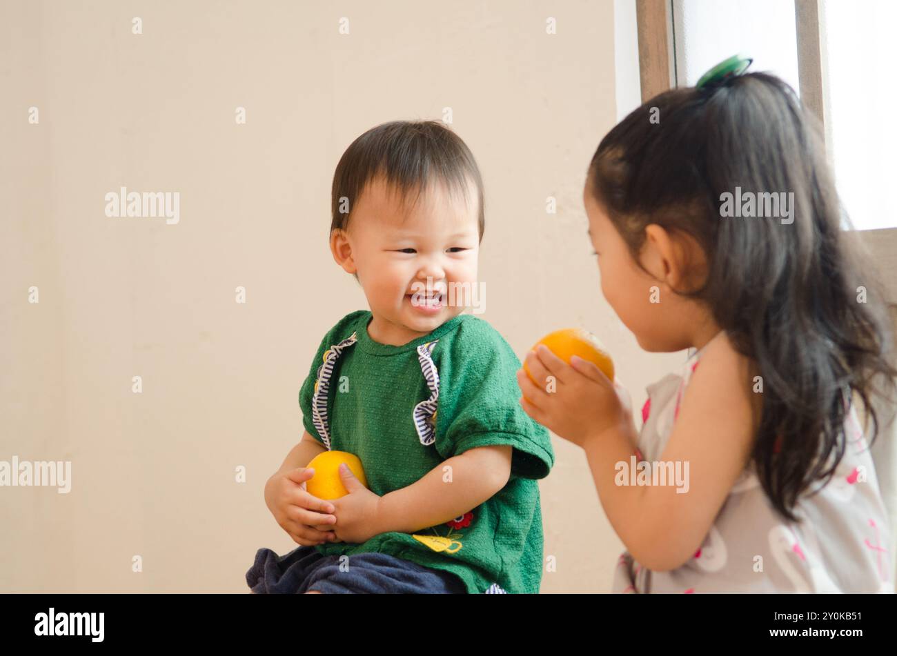 Sisters laughing with?orange Stock Photo - Alamy