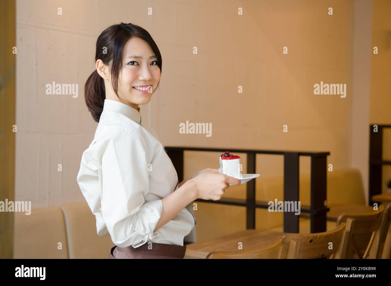 The shop assistant of a cafe with a cake Stock Photo - Alamy