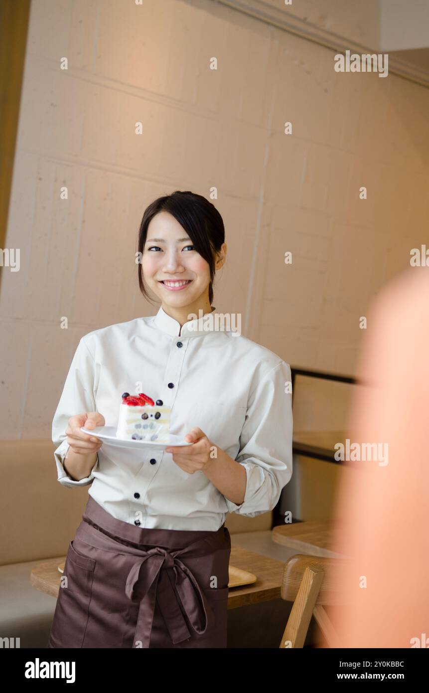 The shop assistant of a cafe with a cake Stock Photo - Alamy