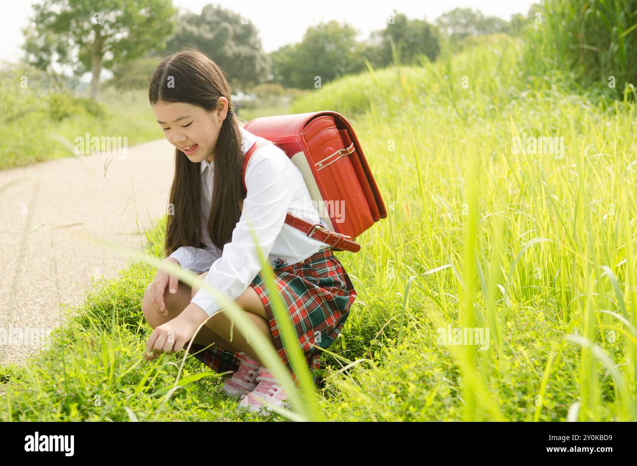Girl with a backpack on the back, squatting down Stock Photo - Alamy