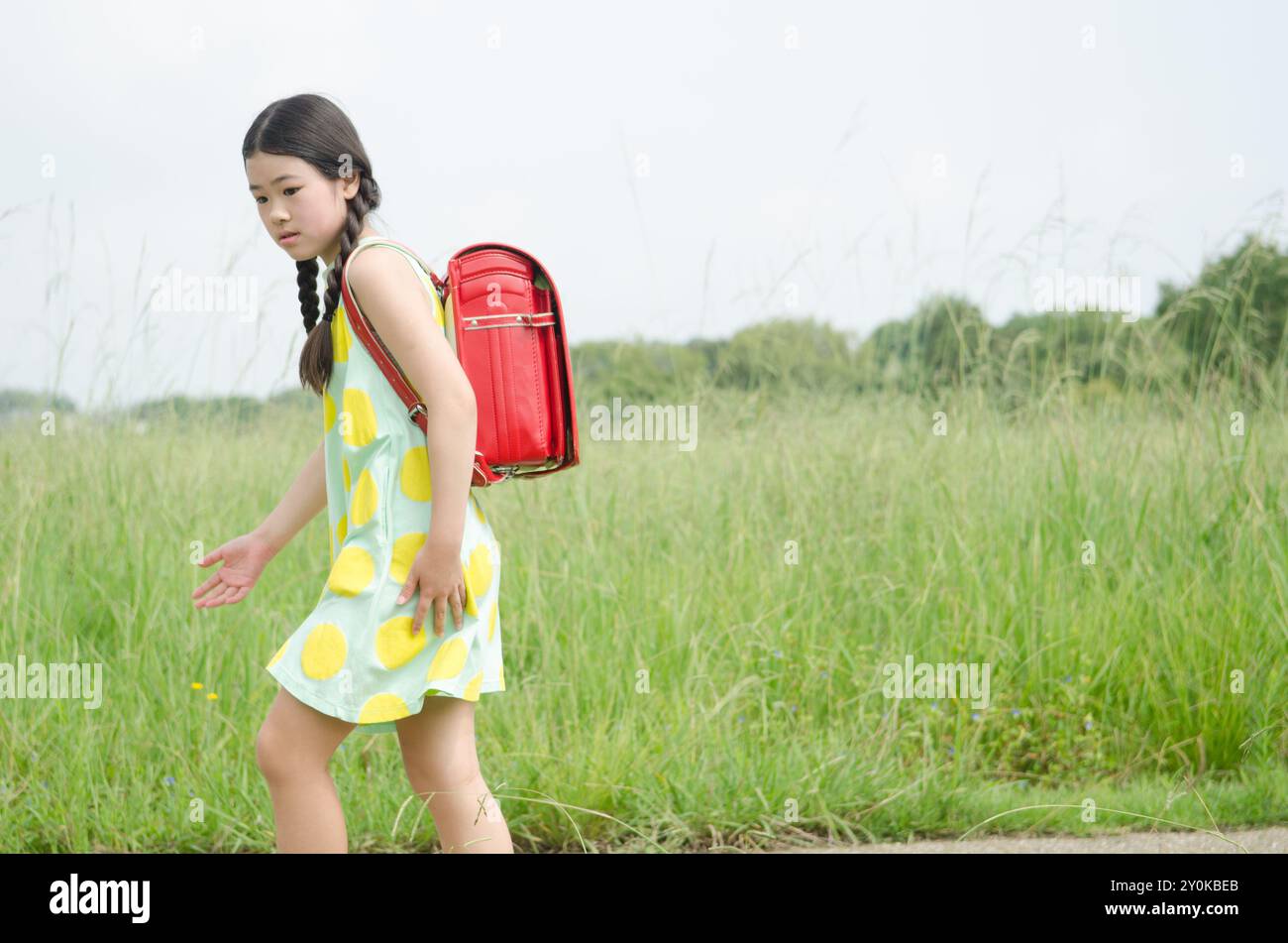 Girl carrying backpack on the back and in a grassy place Stock Photo ...