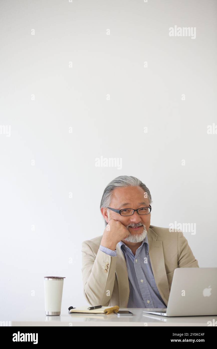 Senior man thinking at the desk Stock Photo - Alamy
