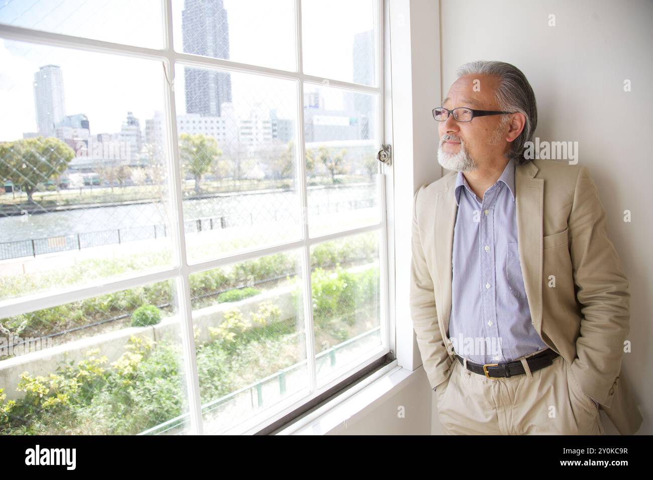 Senior man standing by the window Stock Photo - Alamy