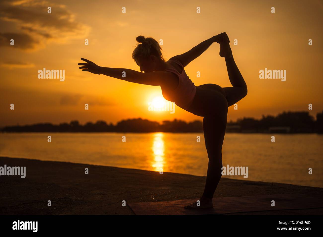 Woman practicing yoga in sunset. Natarajasana / Shiva posture pose ...