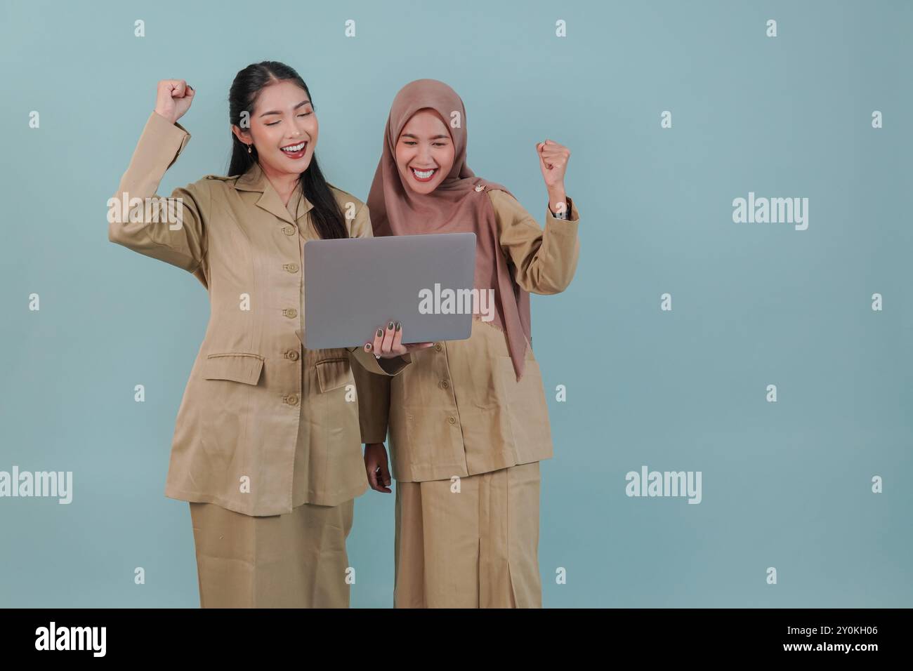 Two joyful government worker woman wearing khaki uniform holding laptop ...