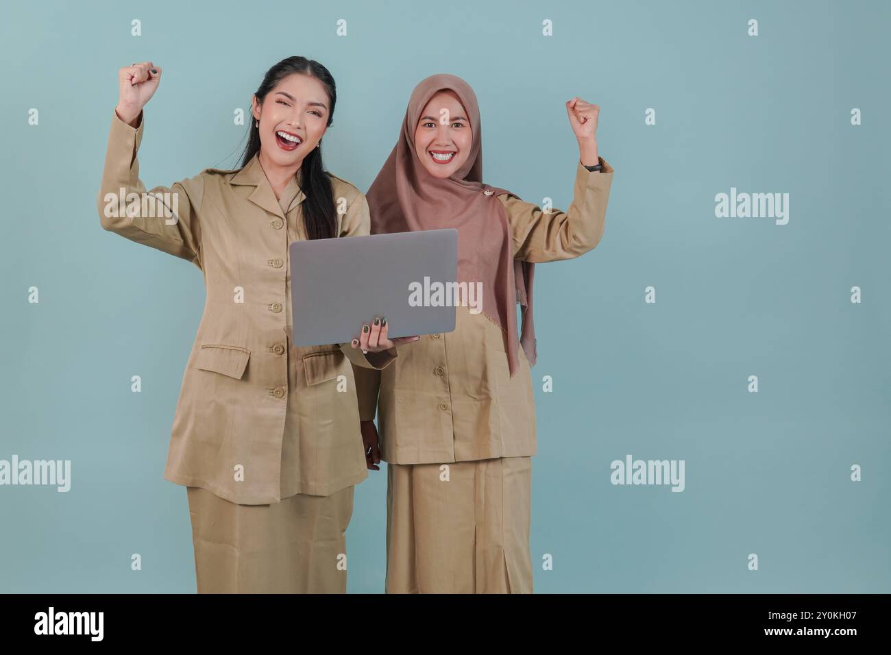 Two joyful government worker woman wearing khaki uniform holding laptop ...
