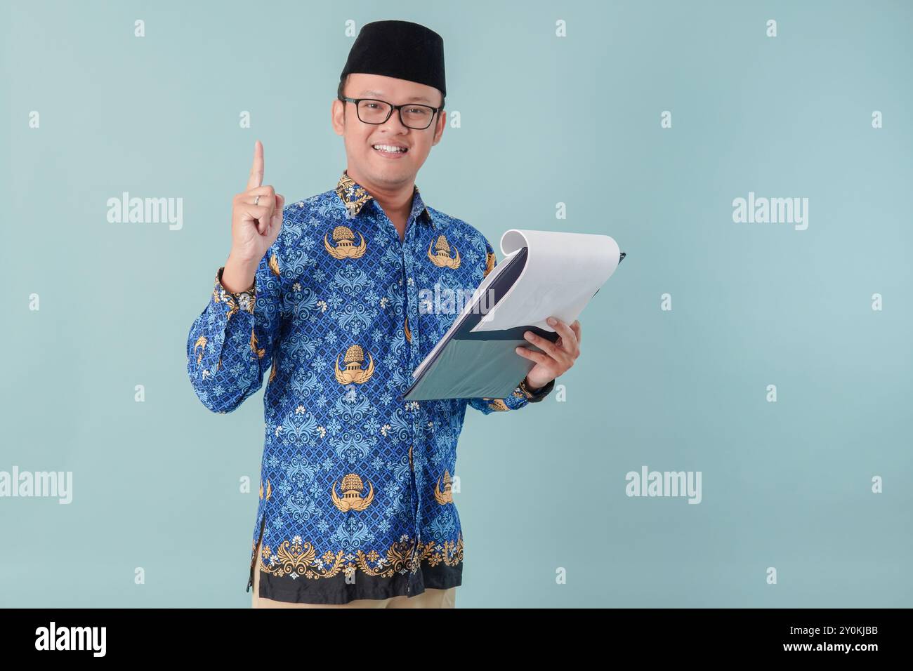 Smiling government worker man wearing blue batik uniform holding ...