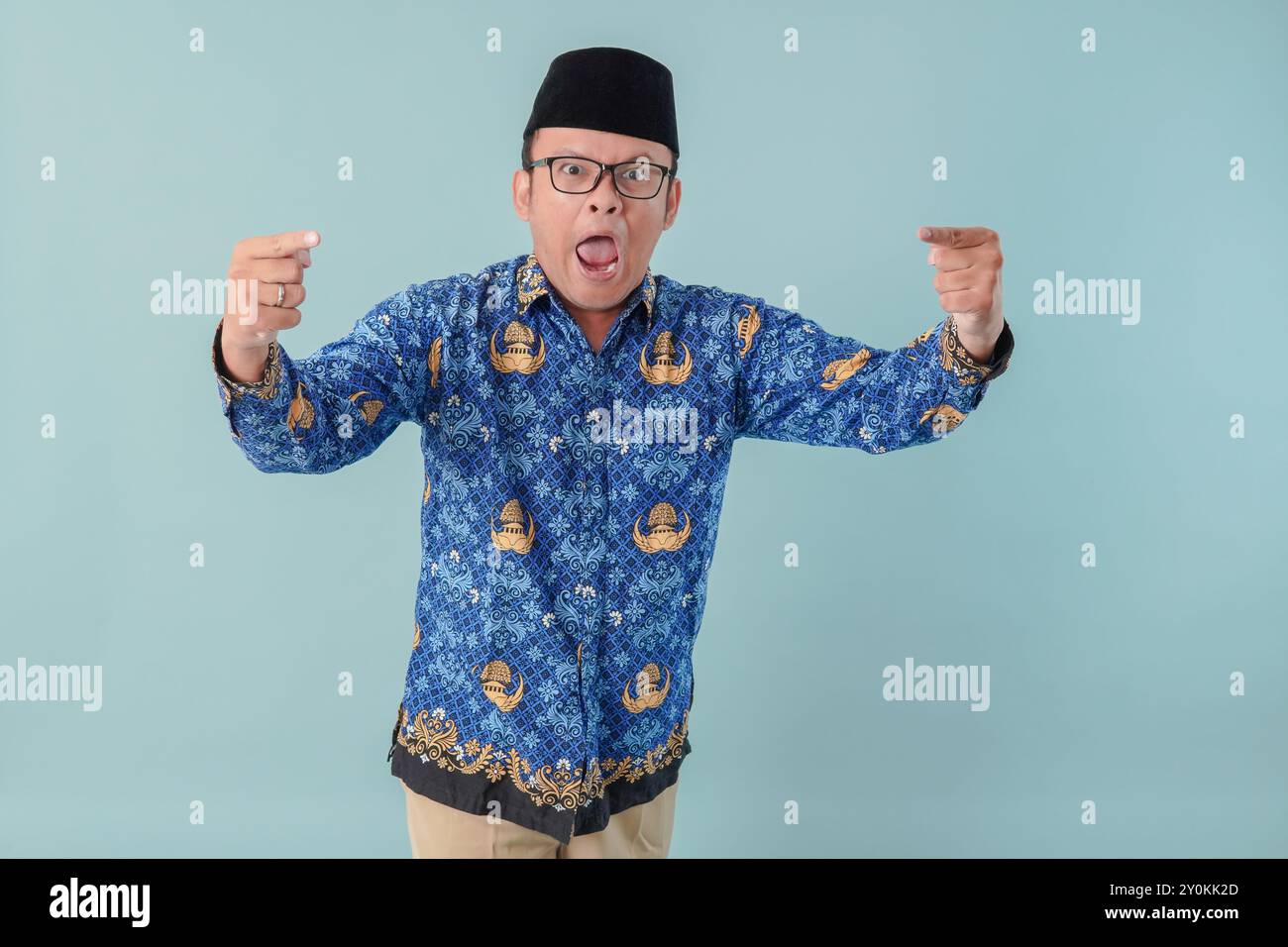 Angry government worker man wearing blue batik uniform raising hands ...