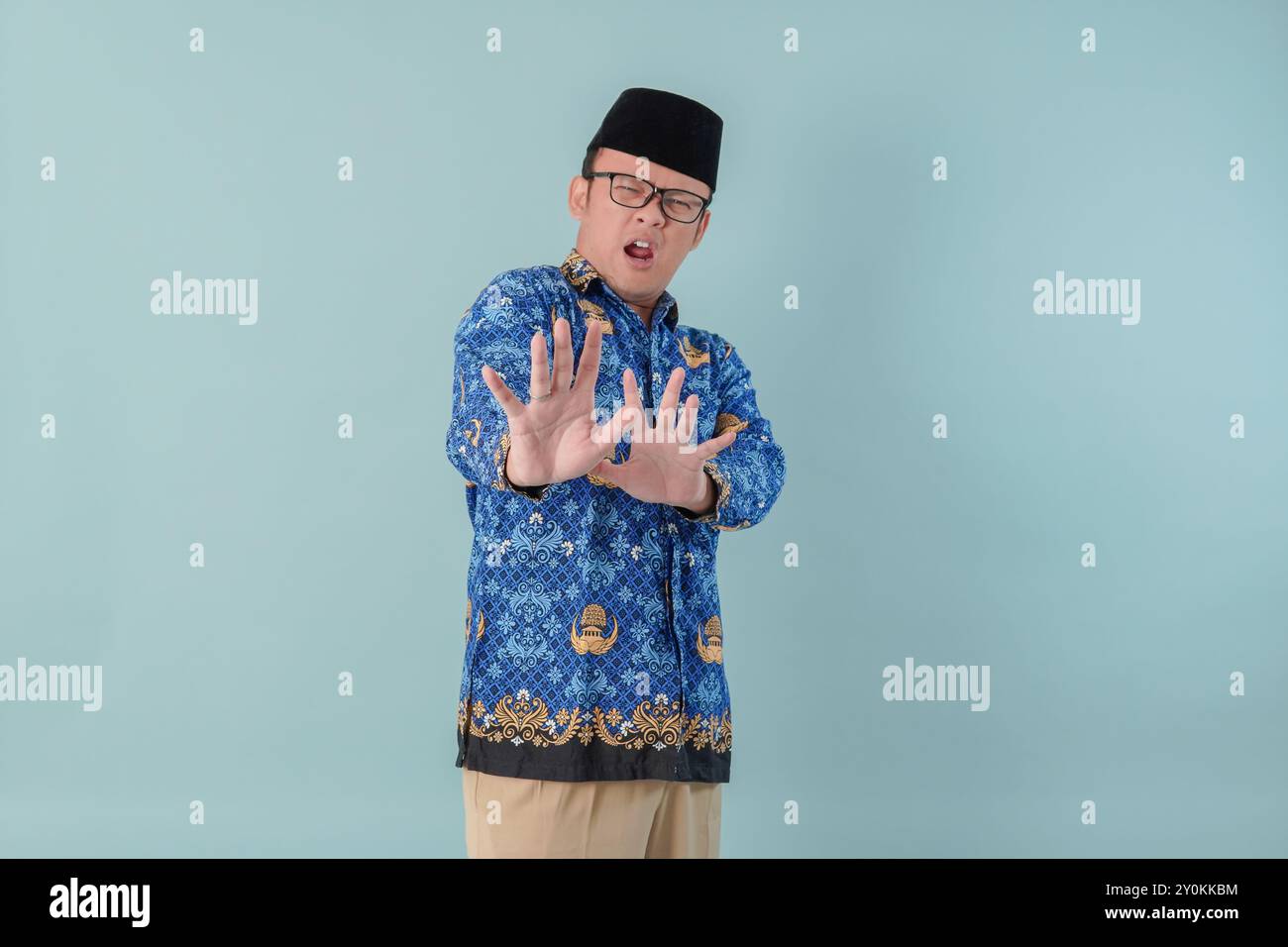 Serious government worker man wearing blue batik uniform with hand ...