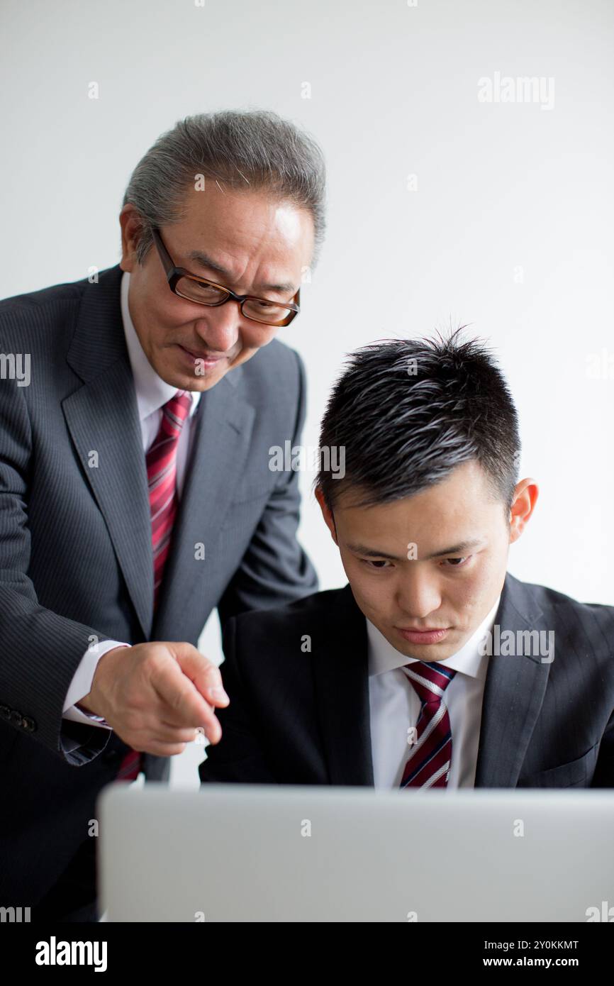 Young businessman and senior businessman watching the computer screen ...