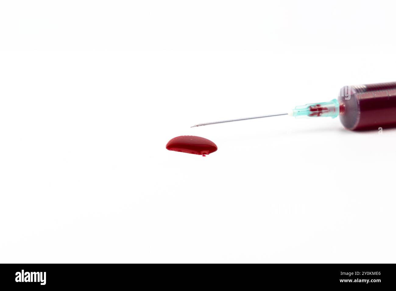 A Horizonal image of a syringe filled with blood, featuring a pool of ...