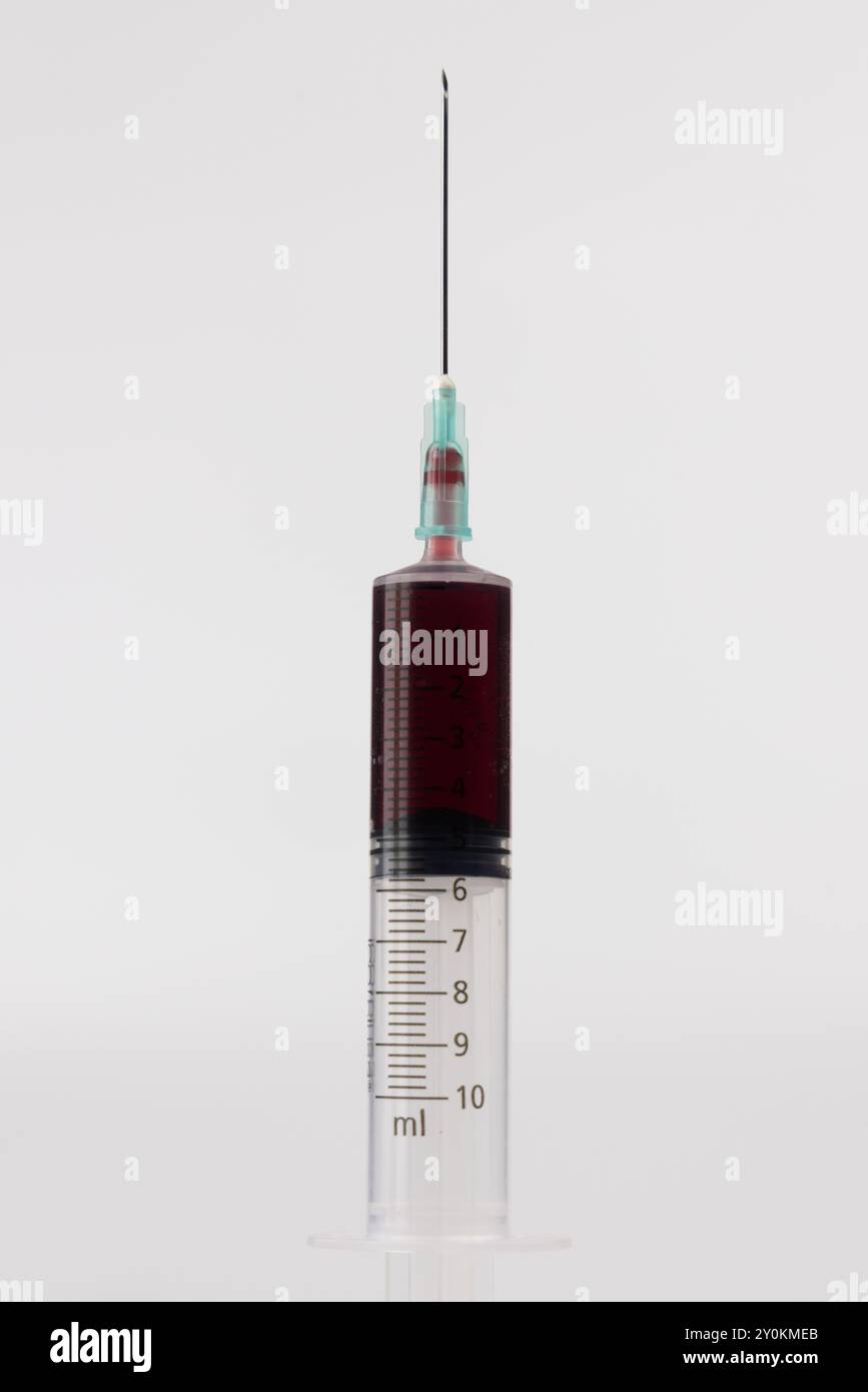 Close-up of a syringe filled with blood, displayed vertically and ...