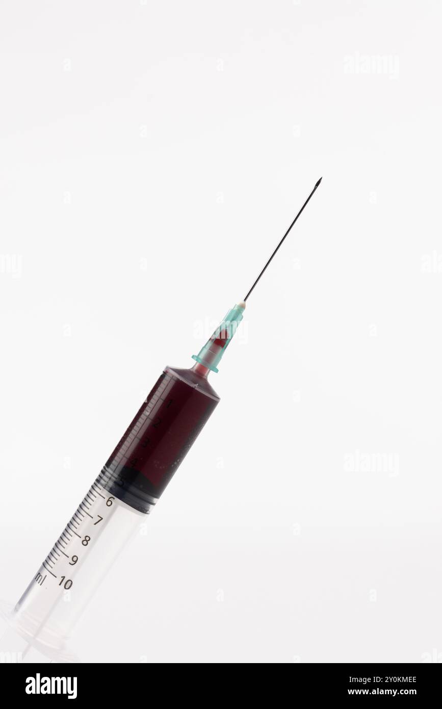 A vertical photo of a syringe filled with blood, prominently positioned ...