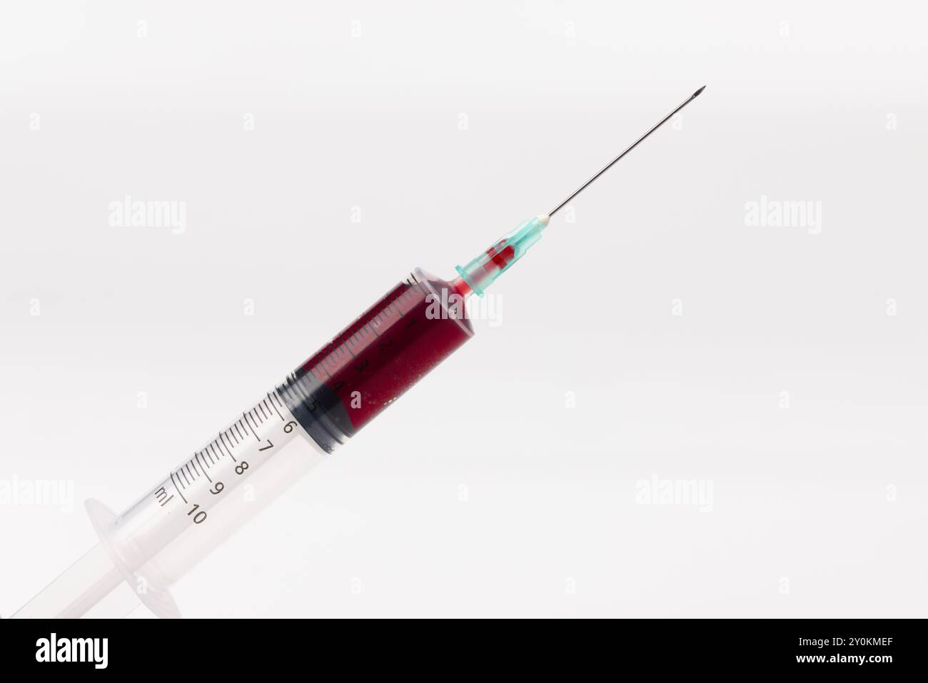 A syringe, filled with bright red blood and angled, placed centrally on ...