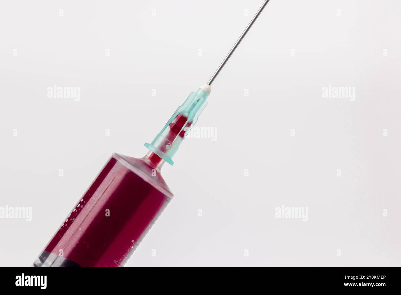 A close-up of a blood-filled syringe, tilted and centered in the photo ...