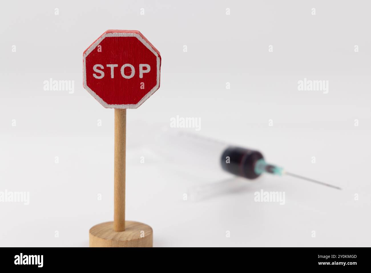 A detailed view of a wooden stop sign with a syringe full of blood in ...