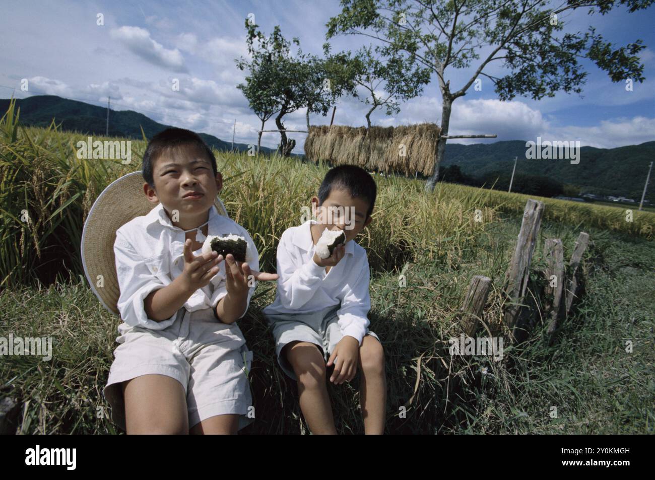 Two boys eating rice balls Stock Photo - Alamy