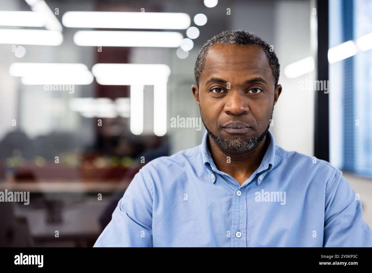 Serious businessman with focused expression in modern office. Wearing ...