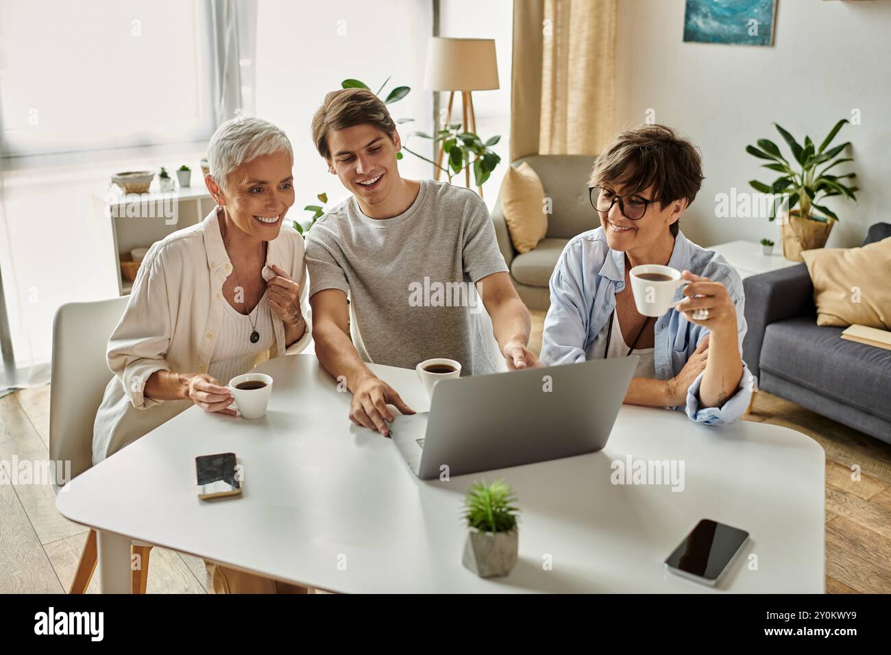 Three family members enjoy a joyful moment together, sharing coffee and ...