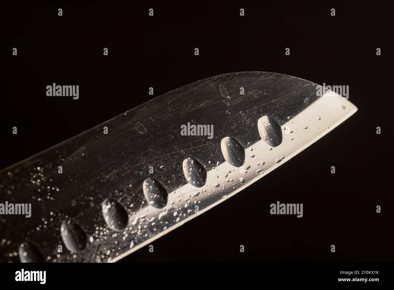 a steel knife covered with water droplets on a blackboard background ...