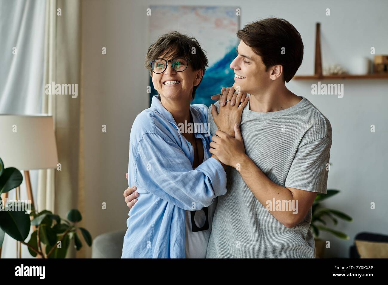 A middle-aged mother joyfully shares a warm embrace with her adult son ...
