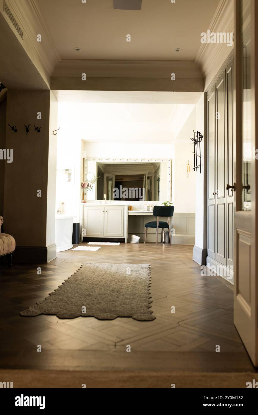 Modern hallway leading to bright bathroom with large mirror and vanity ...