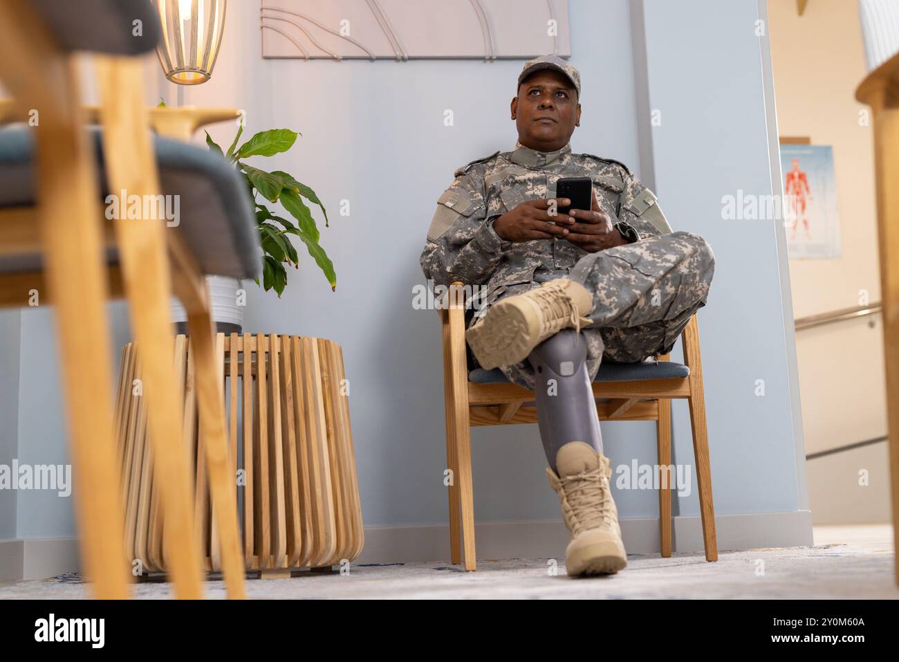 Sitting in chair, soldier with prosthetic leg using smartphone in ...