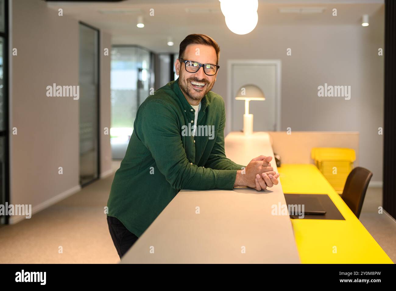 Portrait of happy male manager with hands clasped and in glasses ...