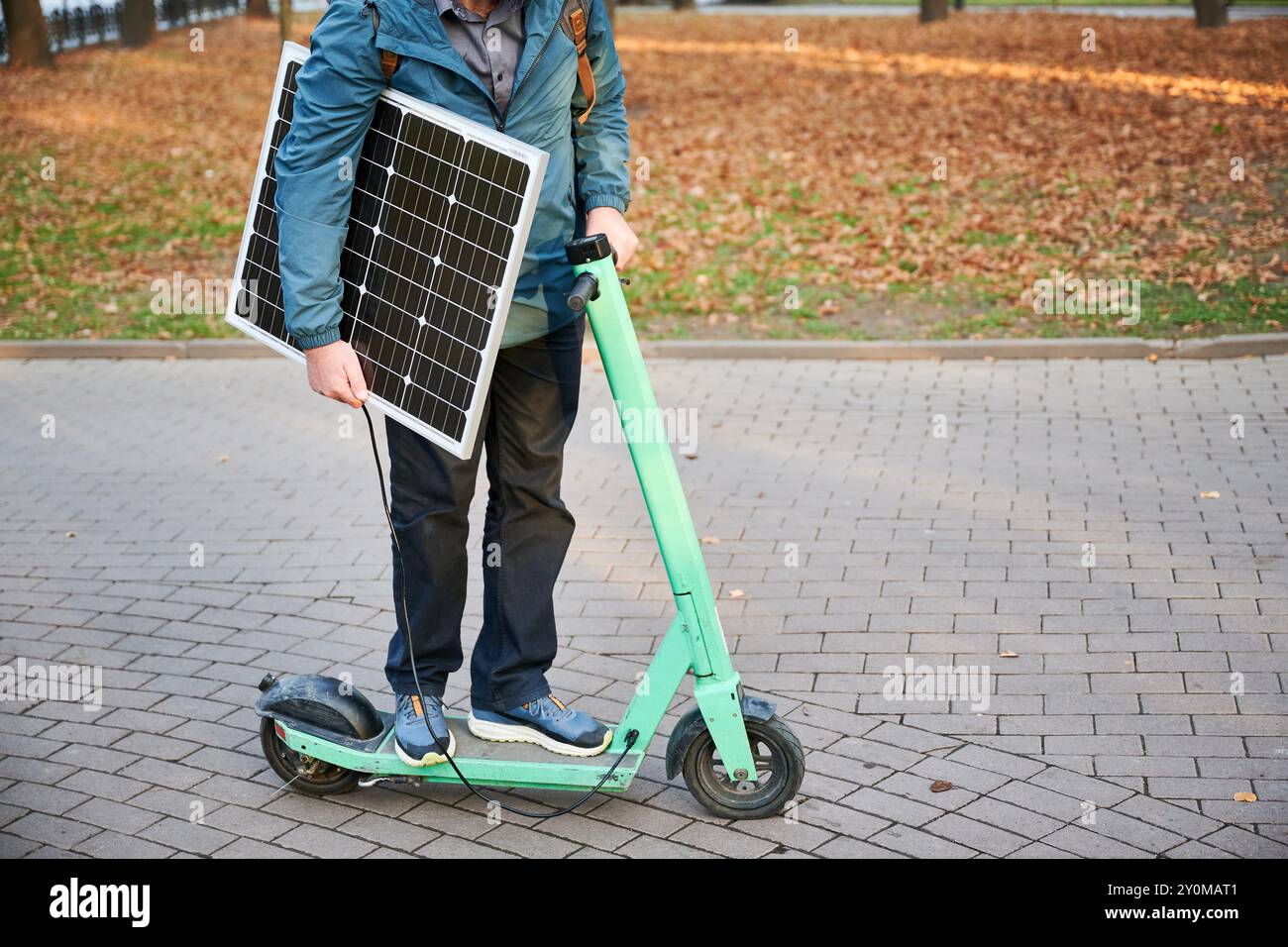 Cropped view of man rides electric scooter while carrying solar panel ...