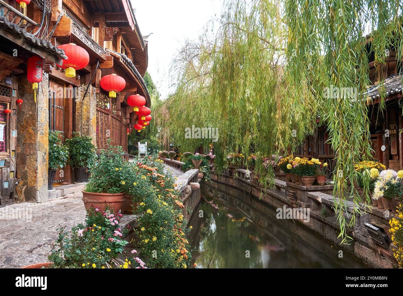 Colourful flowers lining a canal stream next to a cobbled street in ...