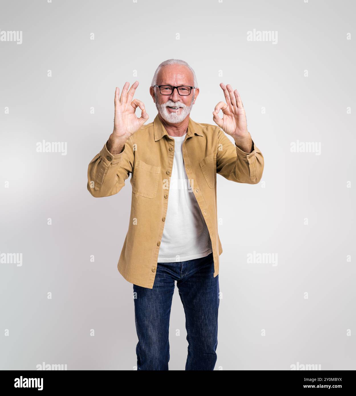 Portrait of successful senior businessman smiling and showing OK signs ...