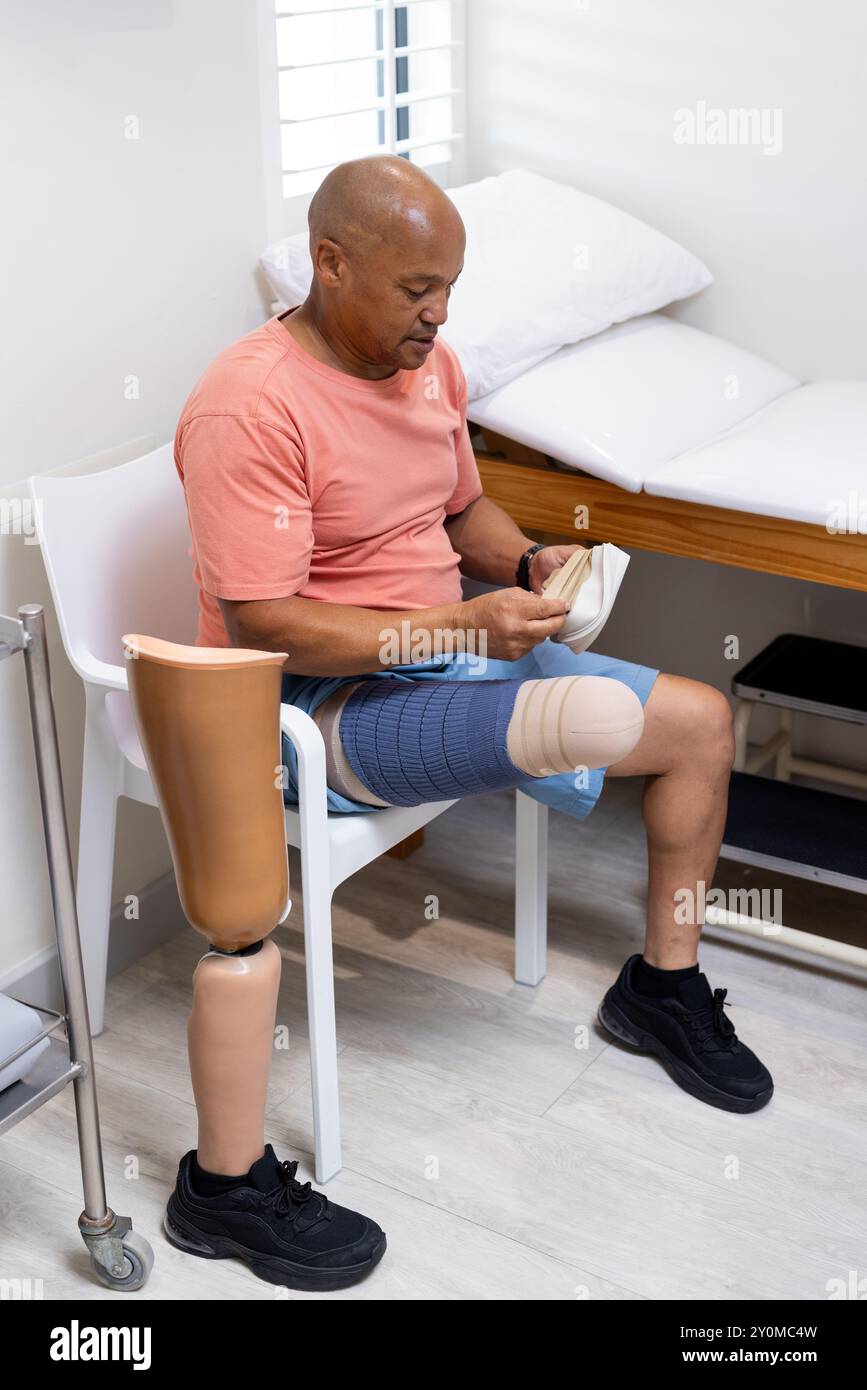 Sitting in chair, man with prosthetic leg reading instruction manual in ...