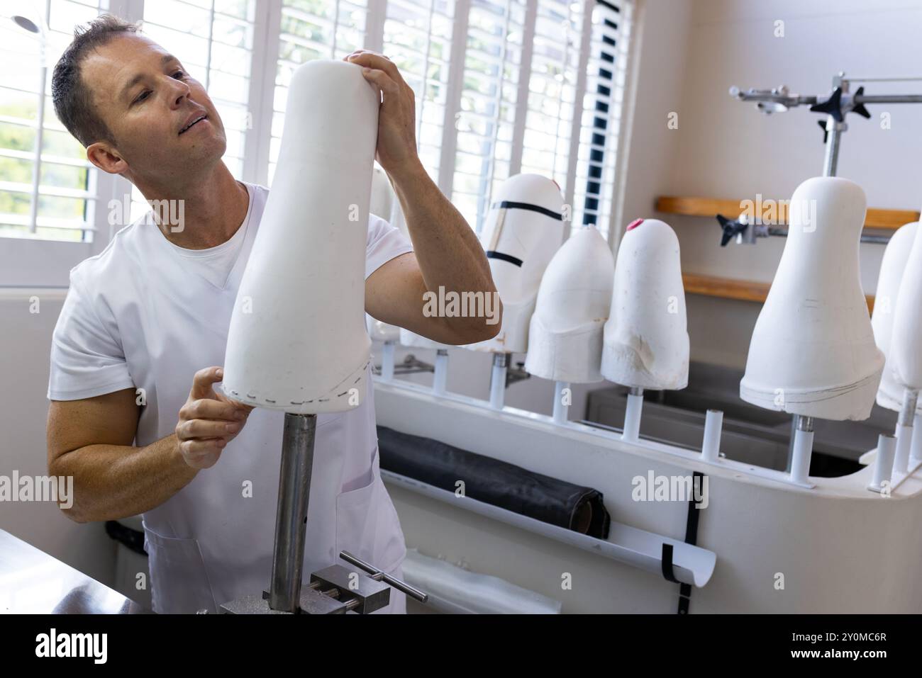 Technician in prosthetic lab adjusting artificial limb mold for patient ...