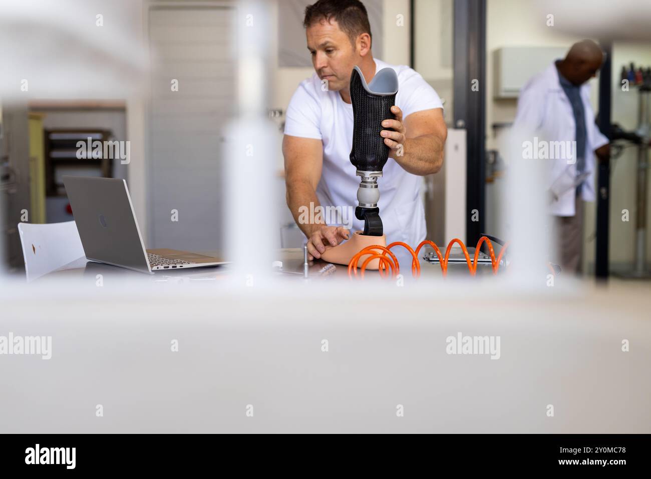 Working in prosthetic lab, man adjusting artificial limb while using ...