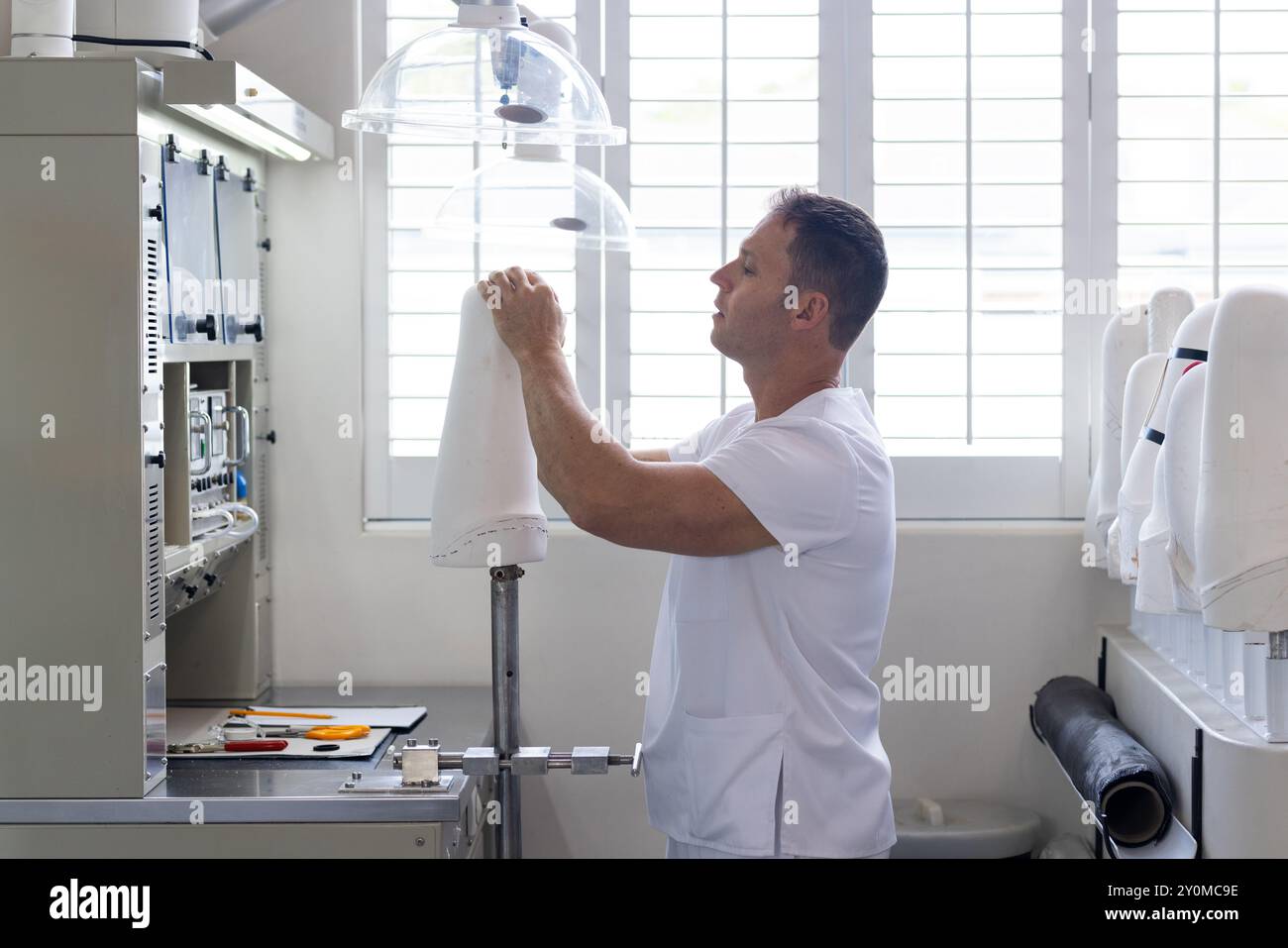 Technician in prosthetic lab adjusting equipment for creating ...