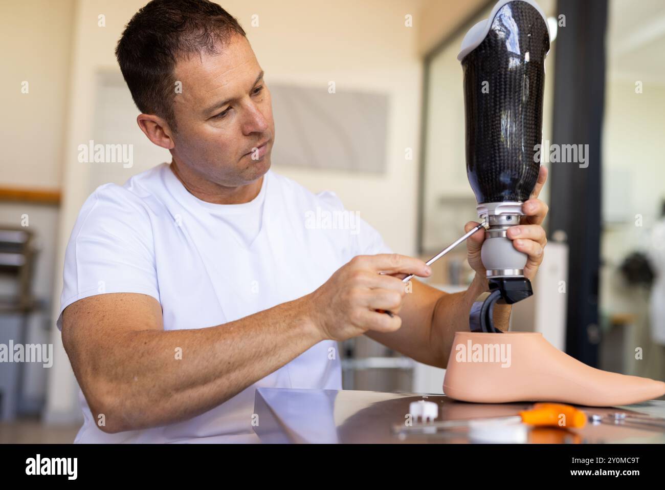 Technician adjusting prosthetic leg with tools in prosthetic lab ...